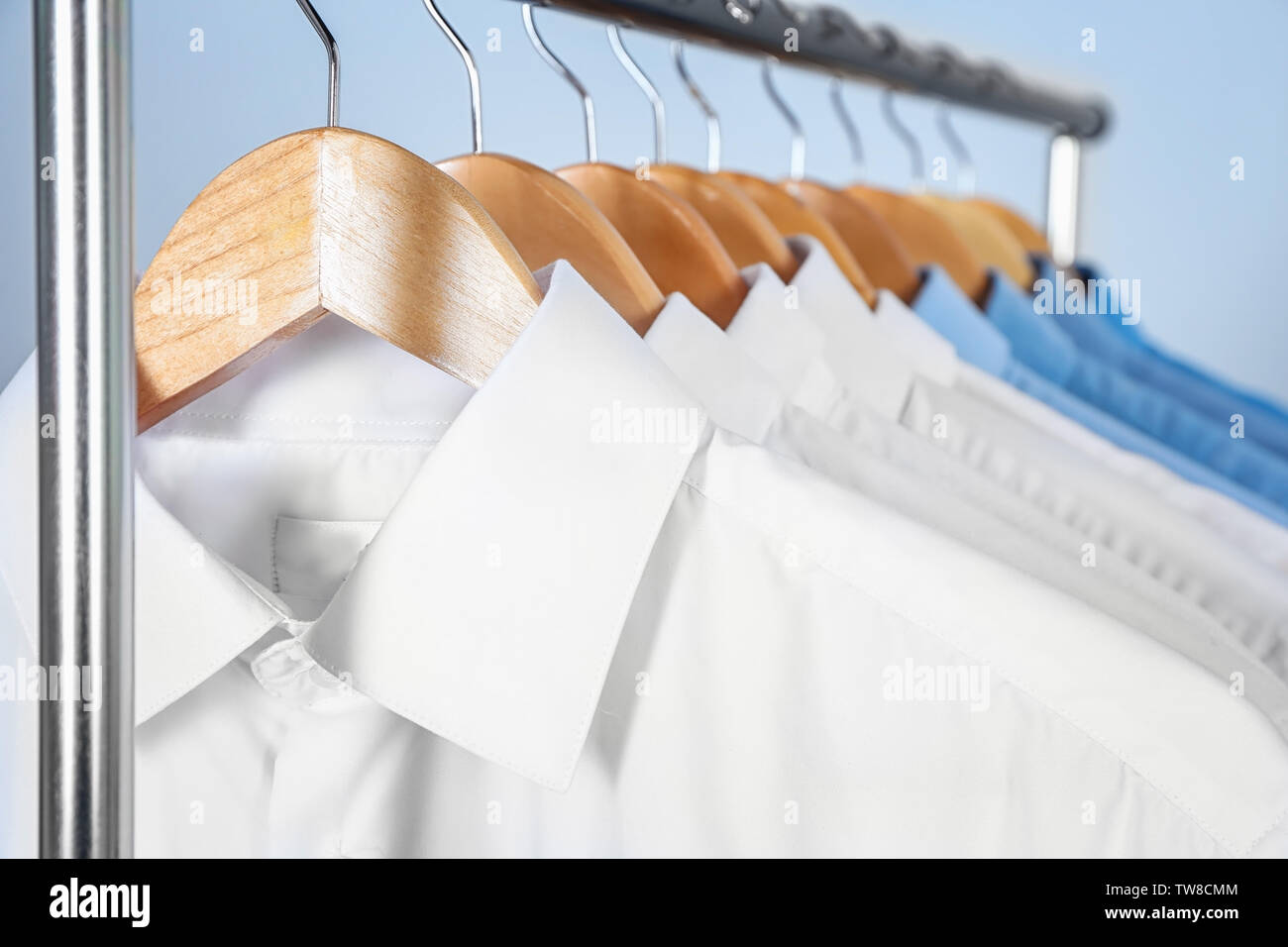 Clean shirts hanging on rack in laundry, closeup Stock Photo - Alamy