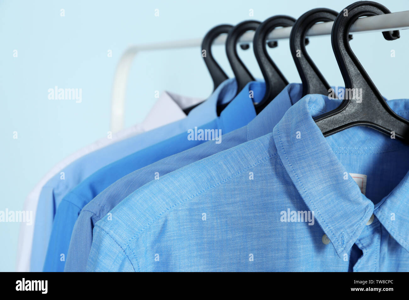Clean shirts hanging on rack in laundry, closeup Stock Photo - Alamy