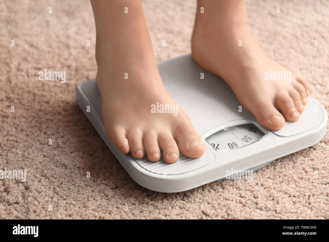 Overweight boy using scales at home Stock Photo - Alamy