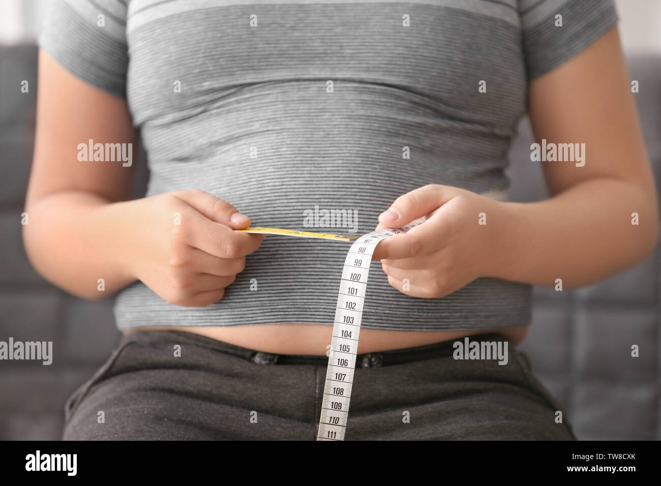 Overweight boy measuring his waist at home, closeup Stock Photo - Alamy