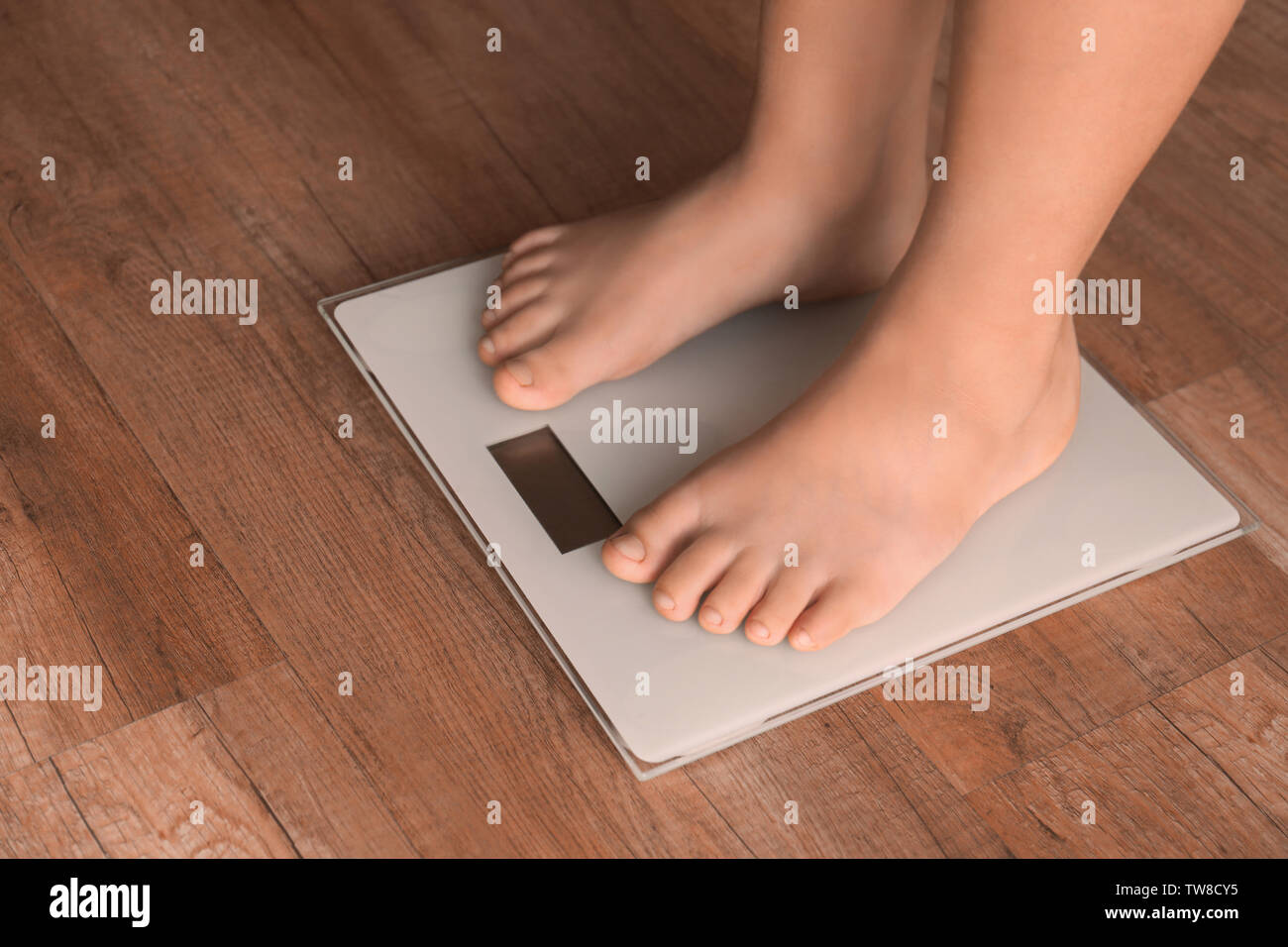 Overweight boy using scales at home Stock Photo - Alamy