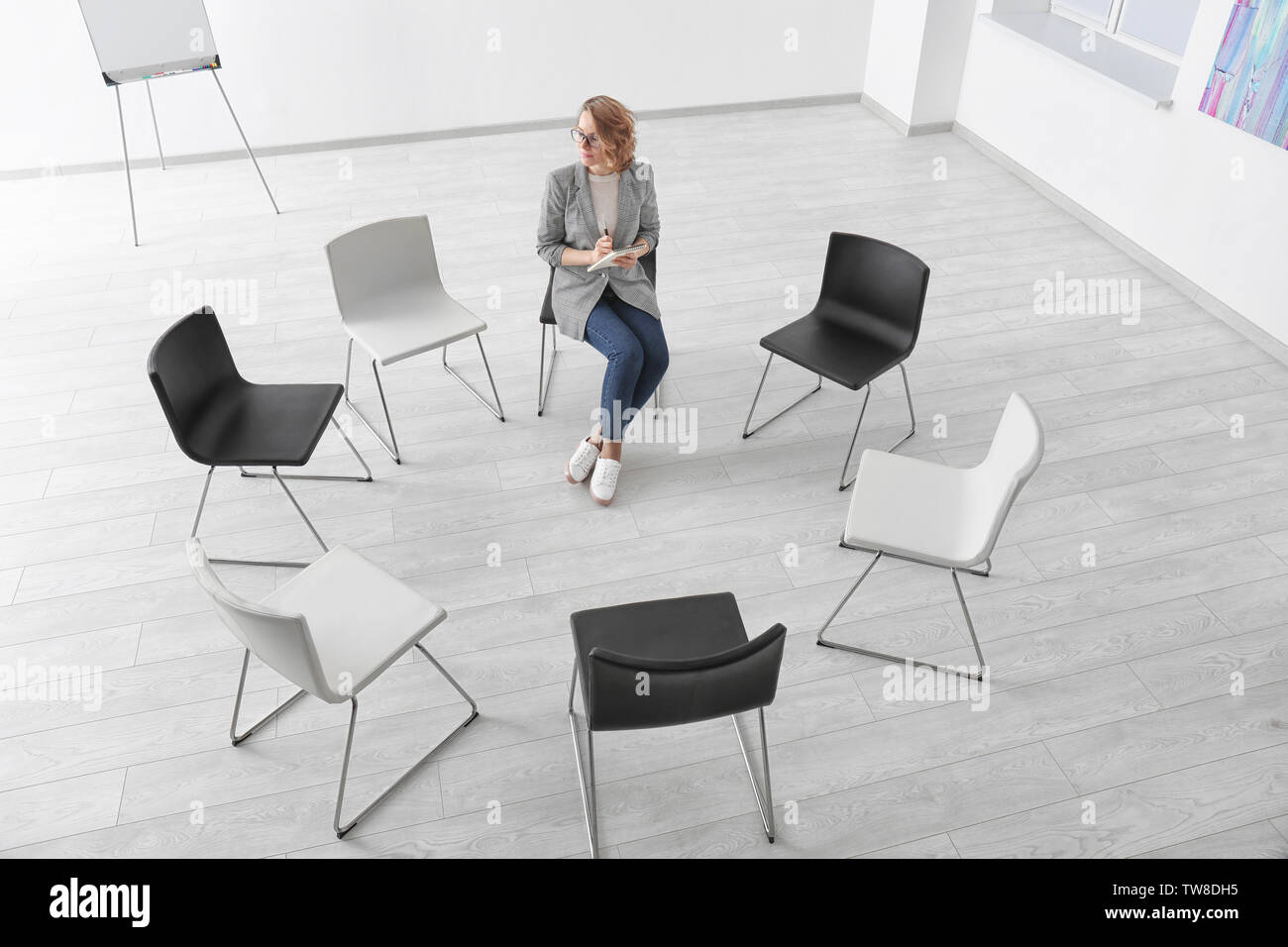 Female psychologist in room with chairs prepared for group ...