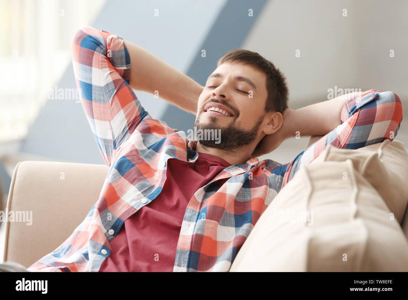 Handsome man relaxing on sofa at home Stock Photo - Alamy