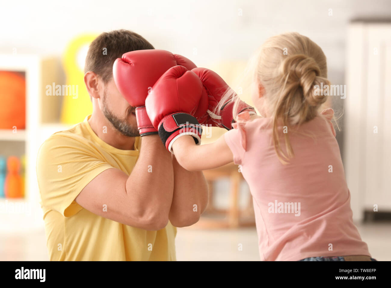 Cute girl and her father in boxing gloves playing at home Stock Photo ...