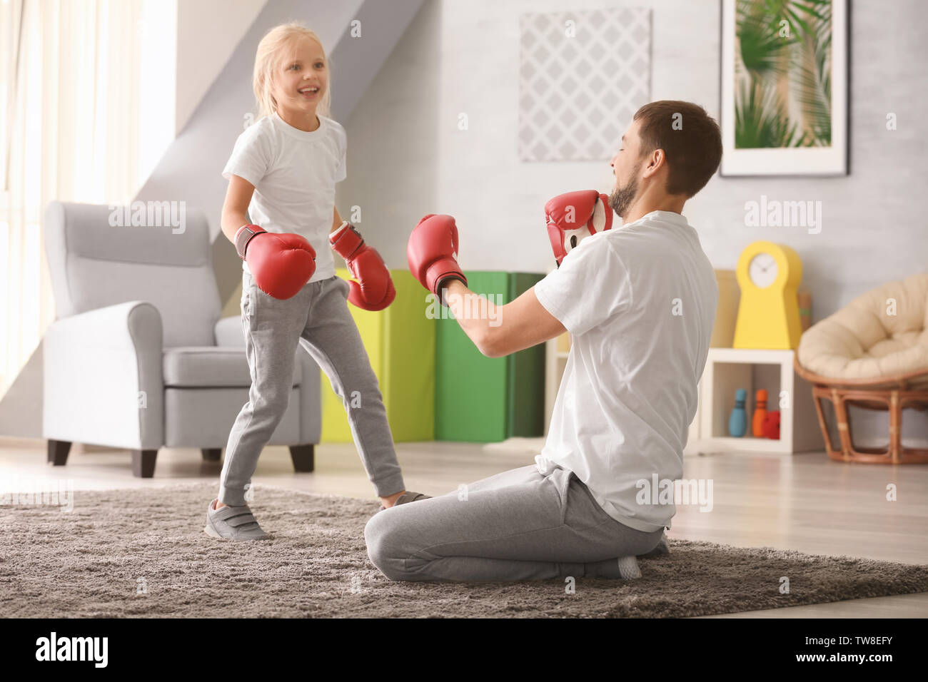 Cute girl and her father in boxing gloves playing at home Stock Photo ...