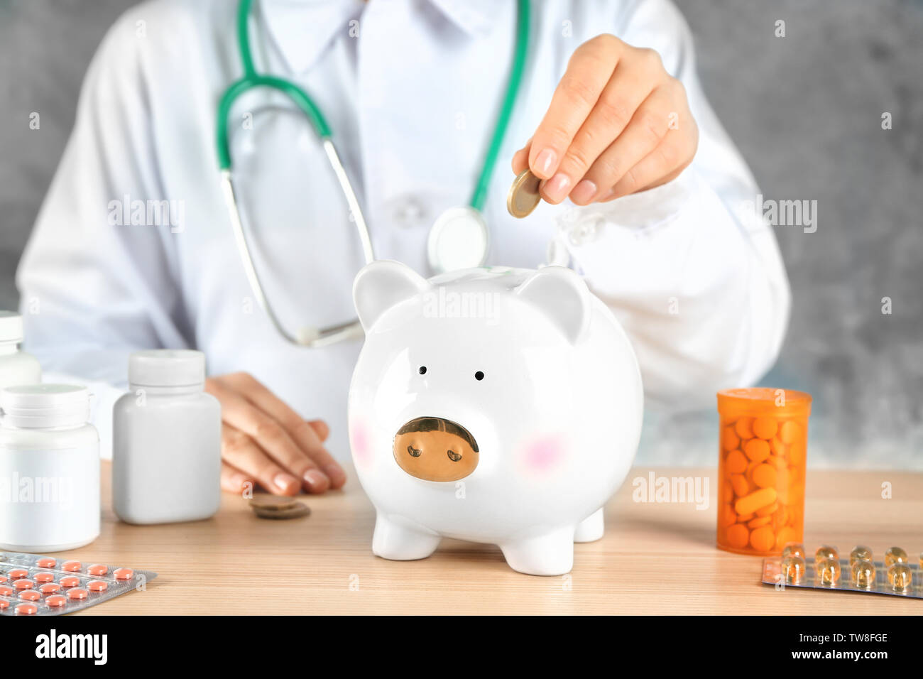 Doctor putting coin into piggy bank. Health care concept Stock Photo ...