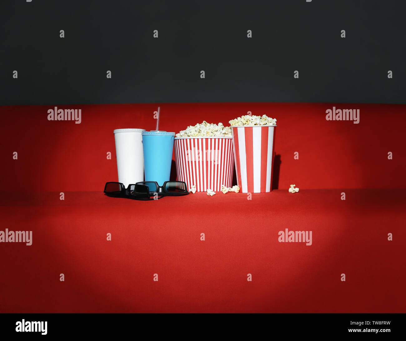 Popcorn and drinks on red sofa in home cinema. Movie night Stock Photo ...