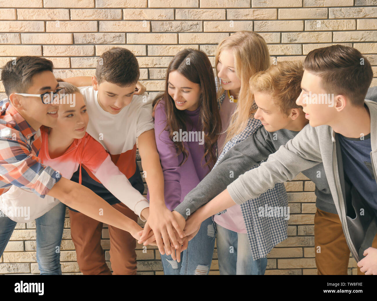 Group of cool teenagers putting hands together as symbol of unity Stock ...