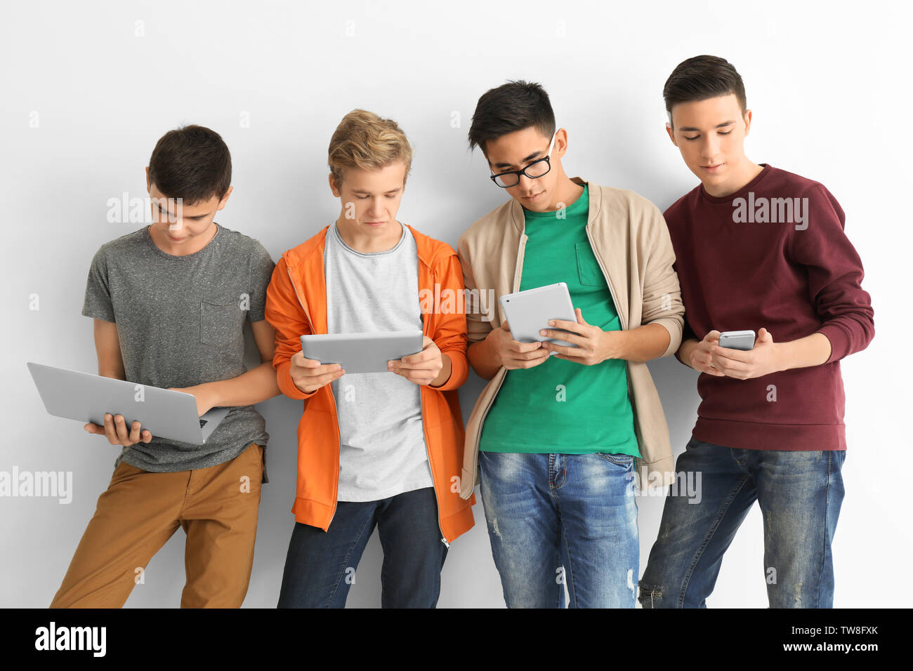 Group of teenagers with modern devices on white background Stock Photo ...