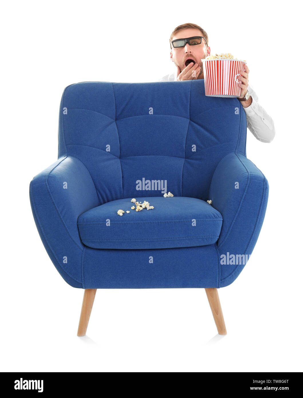 Scared man with 3d glasses and popcorn hiding behind armchair during ...