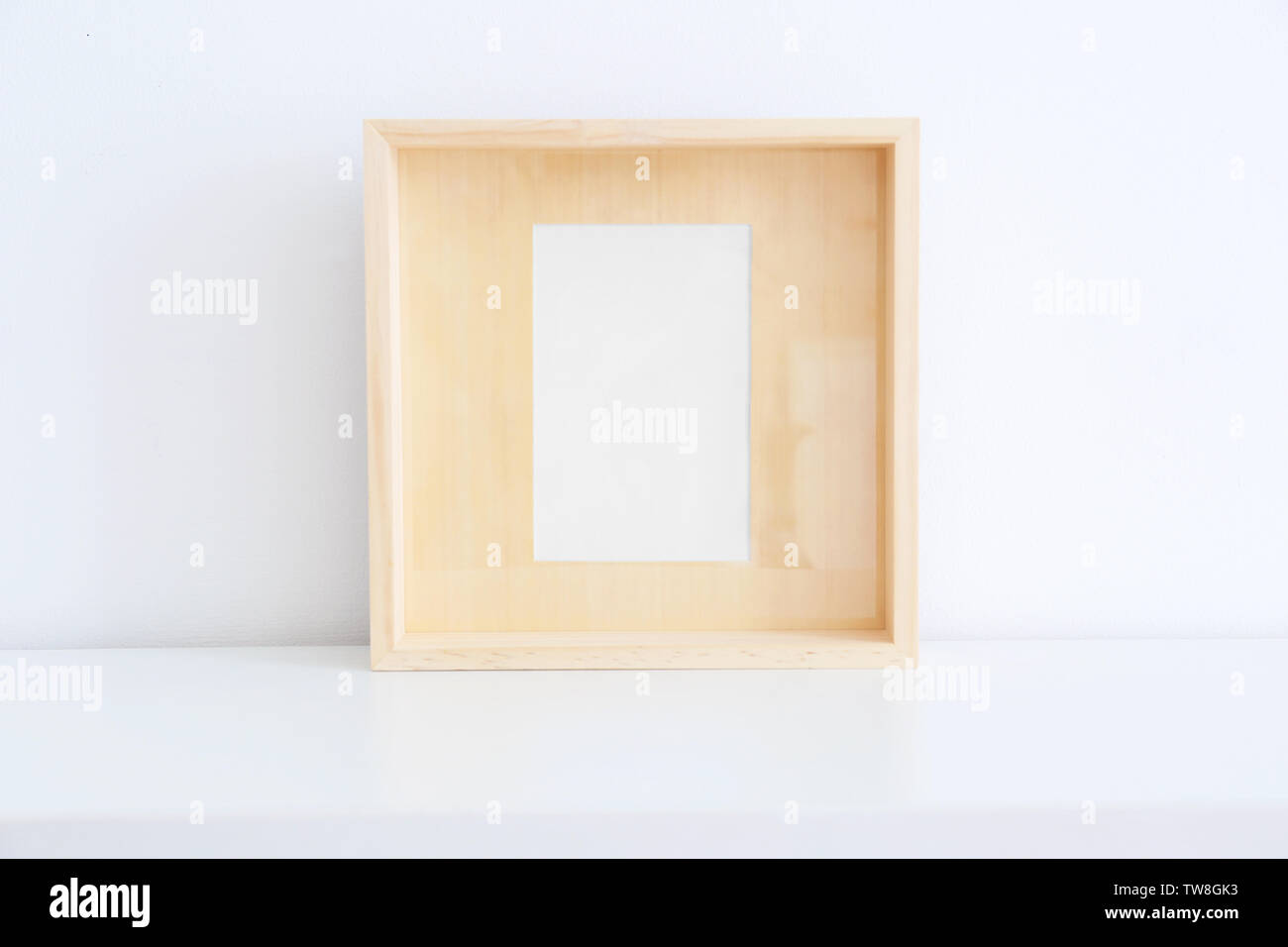 Empty wooden frame on table near white wall Stock Photo - Alamy