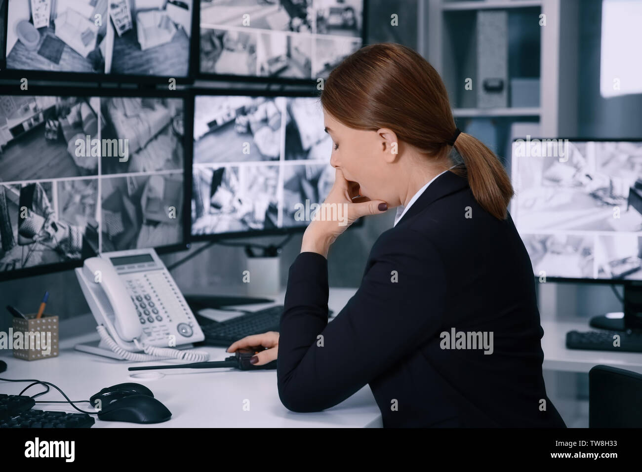 Tired female security guard in surveillance room Stock Photo - Alamy