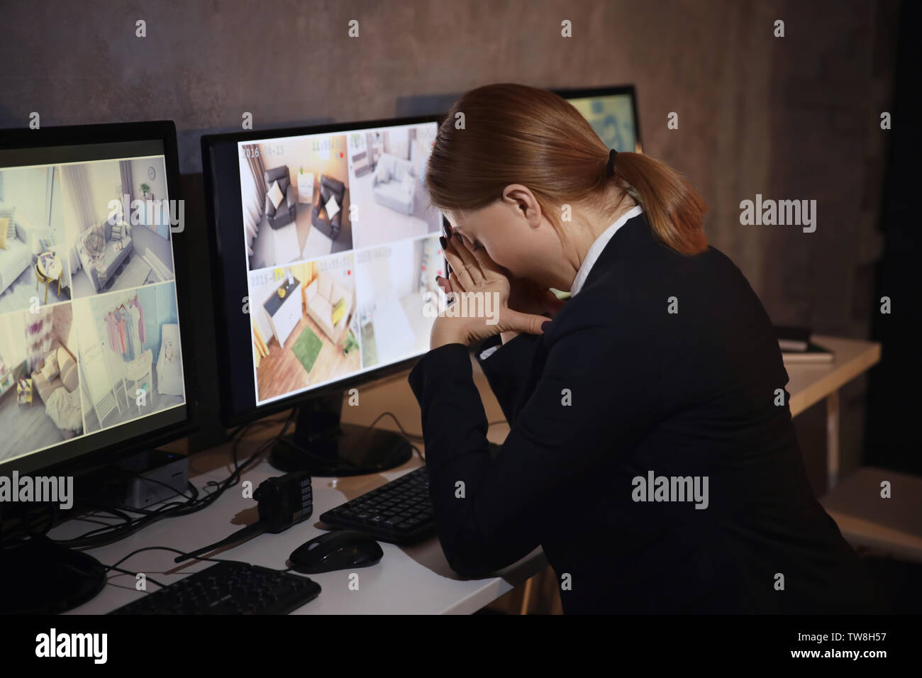 Tired female security guard in surveillance room Stock Photo - Alamy