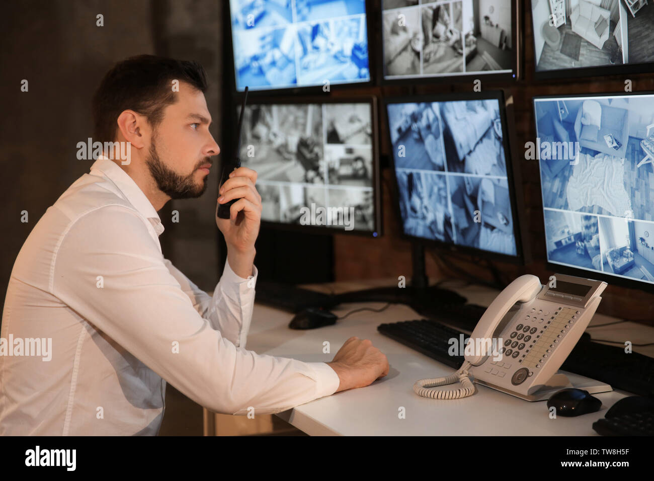 Male security guard using radio transmitter in surveillance room Stock ...