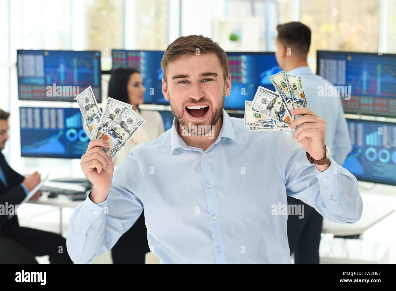 Happy male stock trader with dollar bills in office Stock Photo - Alamy