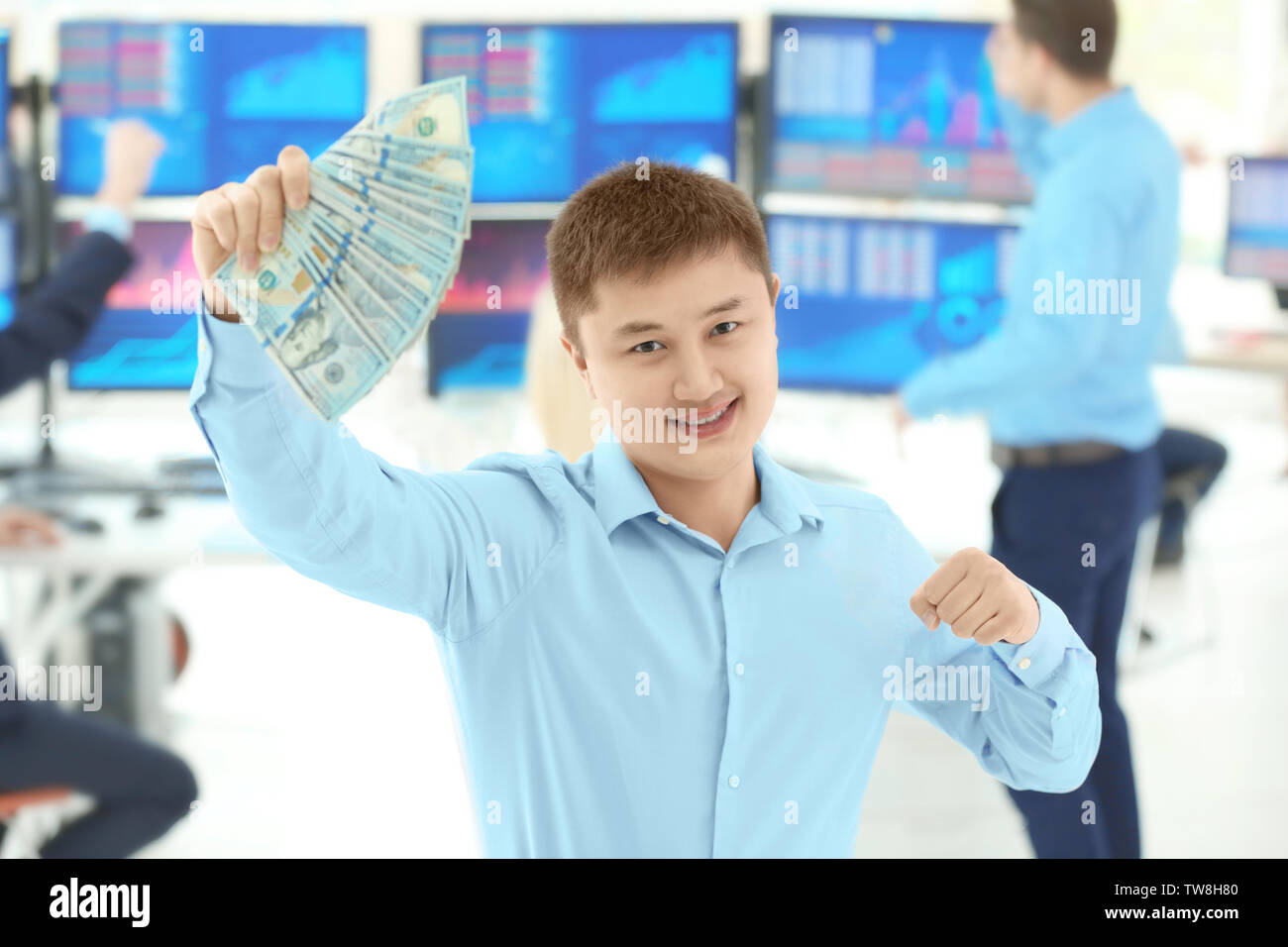Happy male stock trader with dollar bills in office Stock Photo - Alamy