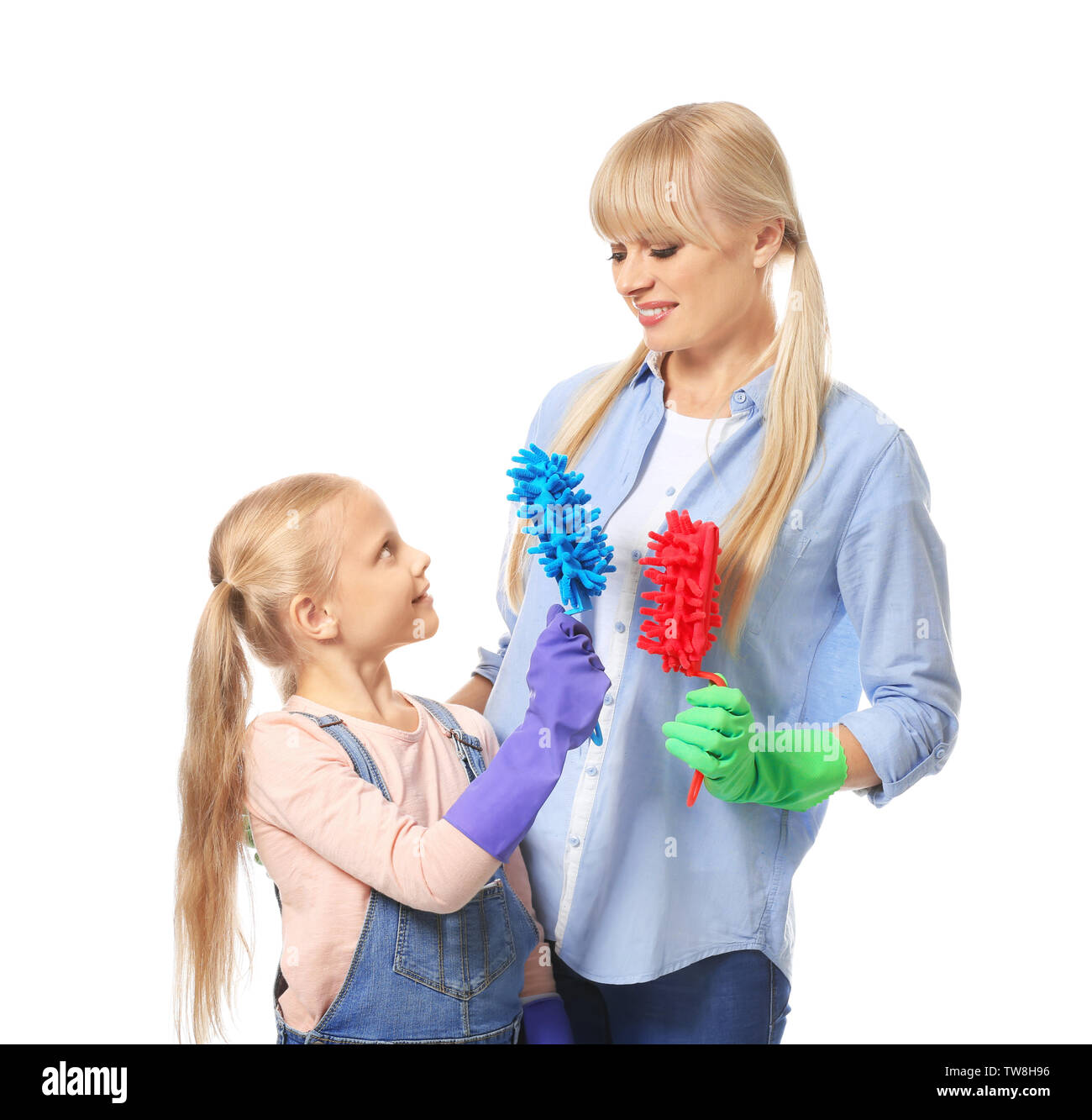 Little girl and her mother with cleaning supplies on white background ...
