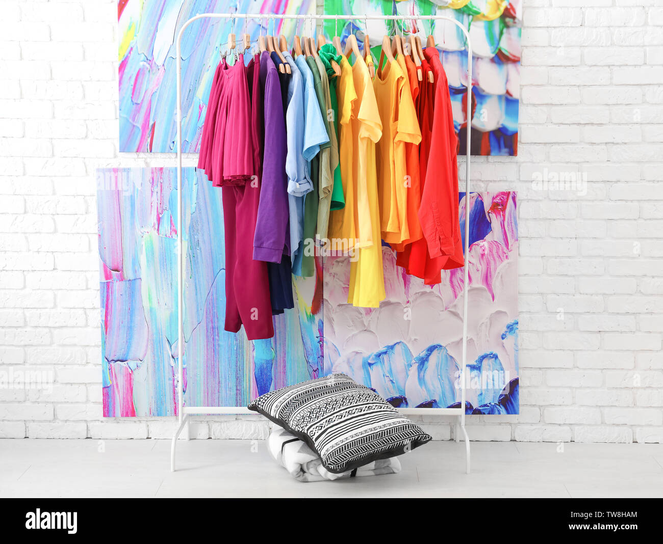 Rack with rainbow clothes near brick wall Stock Photo - Alamy