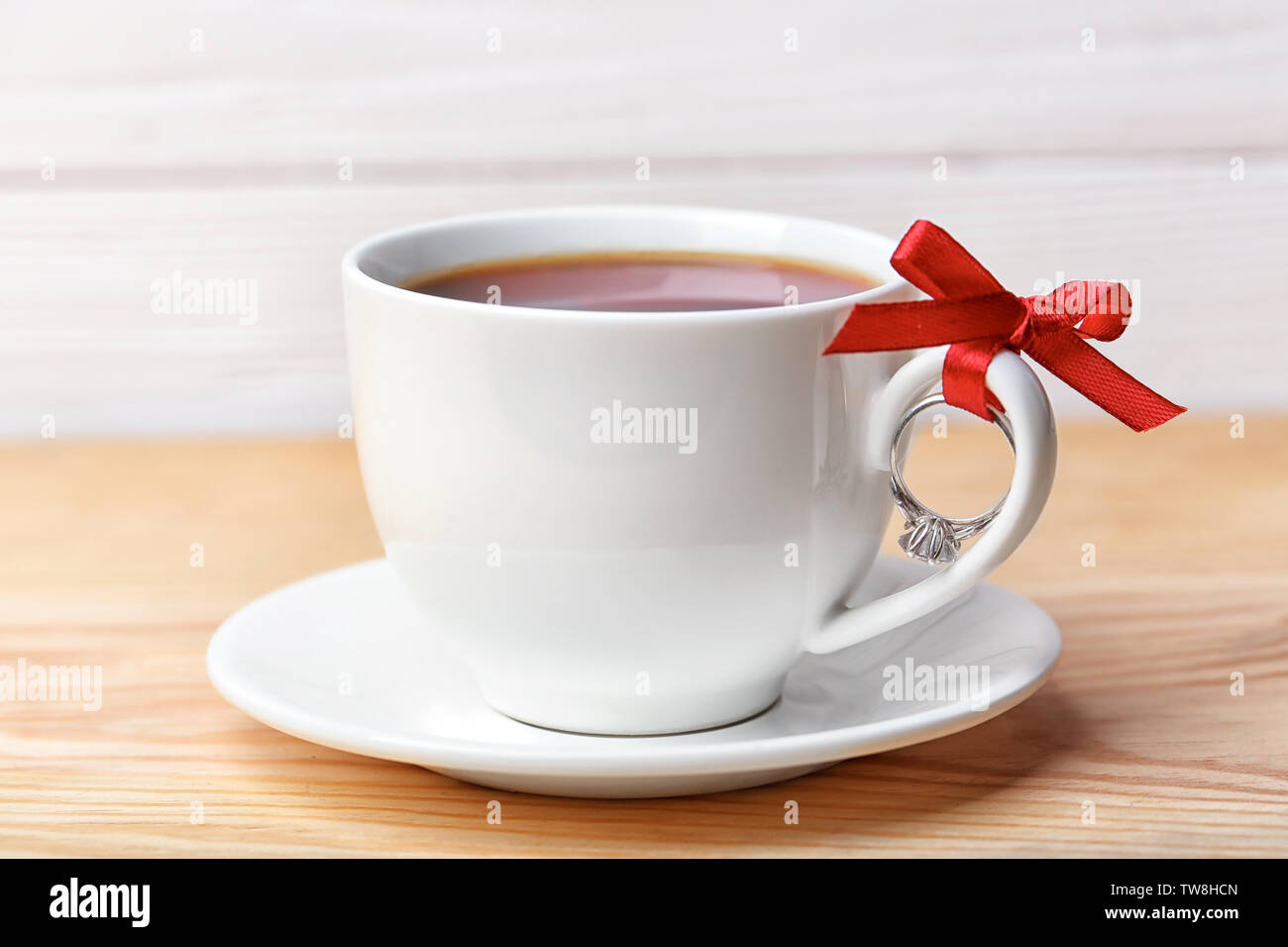 Engagement ring tied to cup of coffee on table, closeup Stock Photo - Alamy
