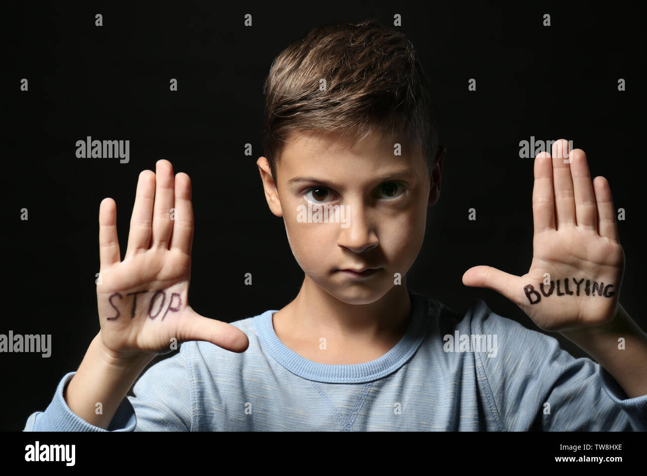 Little boy with words "Stop bullying" on his hands against black ...