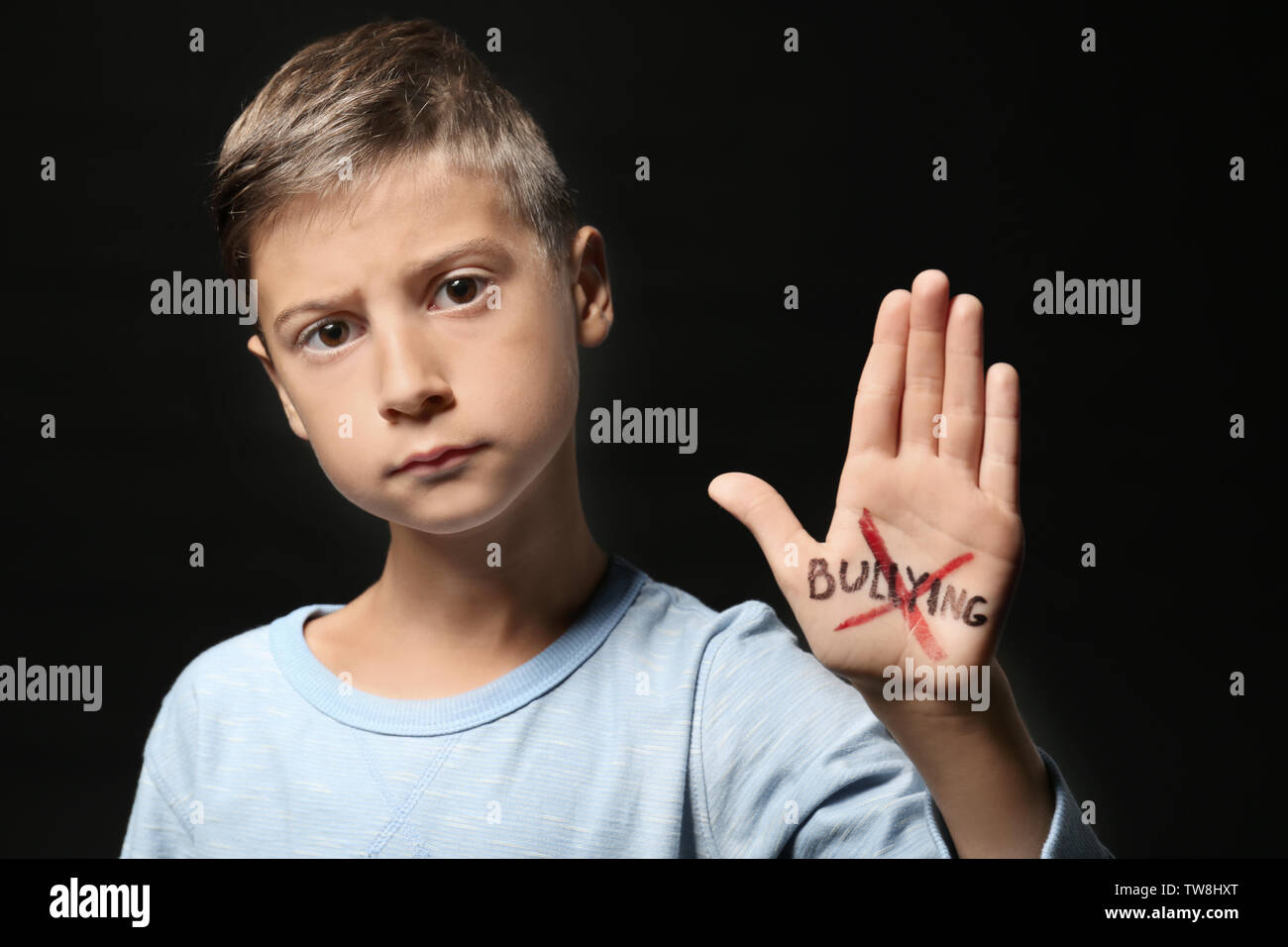 Little boy with crossed word "Bullying" on his hand against black ...