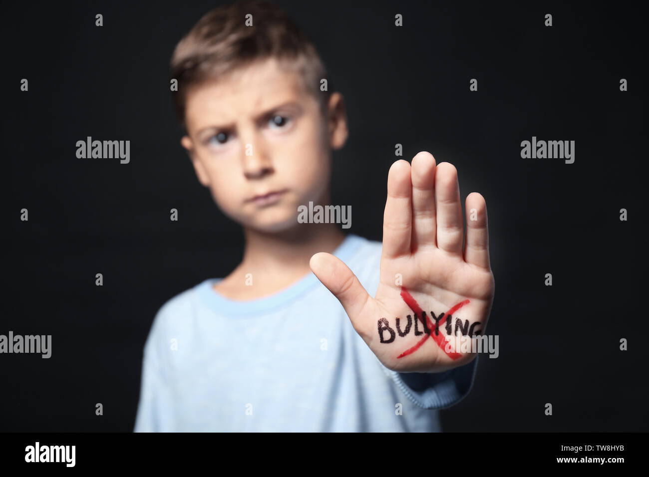 Little boy with crossed word "Bullying" on his hand against black ...