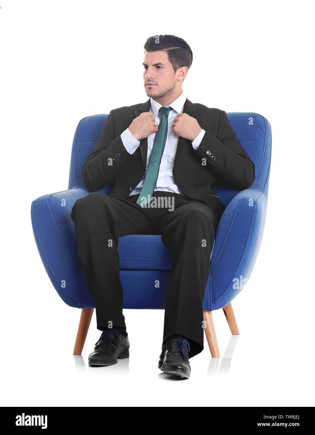 Handsome young man sitting in armchair on white background Stock Photo ...