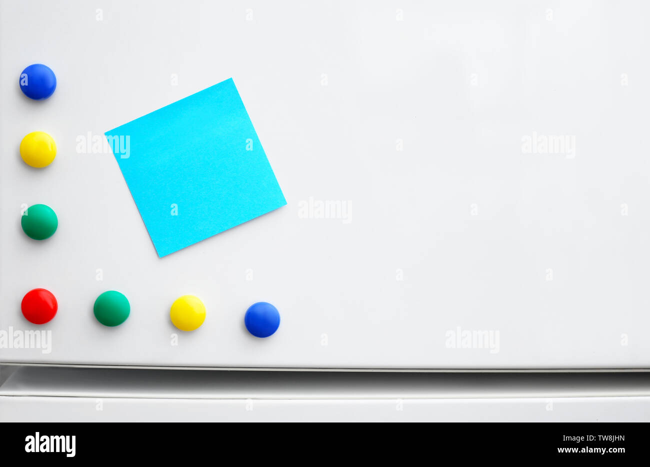 Empty sticky note and colorful magnets on refrigerator door, closeup ...