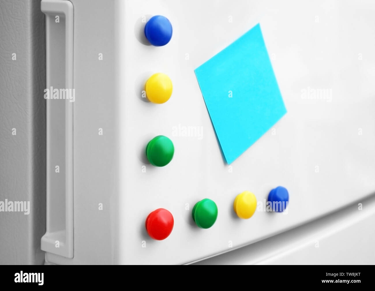 Empty sticky note and colorful magnets on refrigerator door, closeup ...