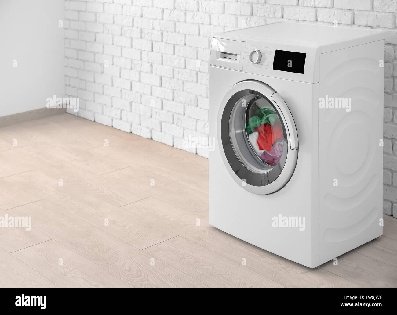Laundry in washing machine on brick wall background Stock Photo - Alamy