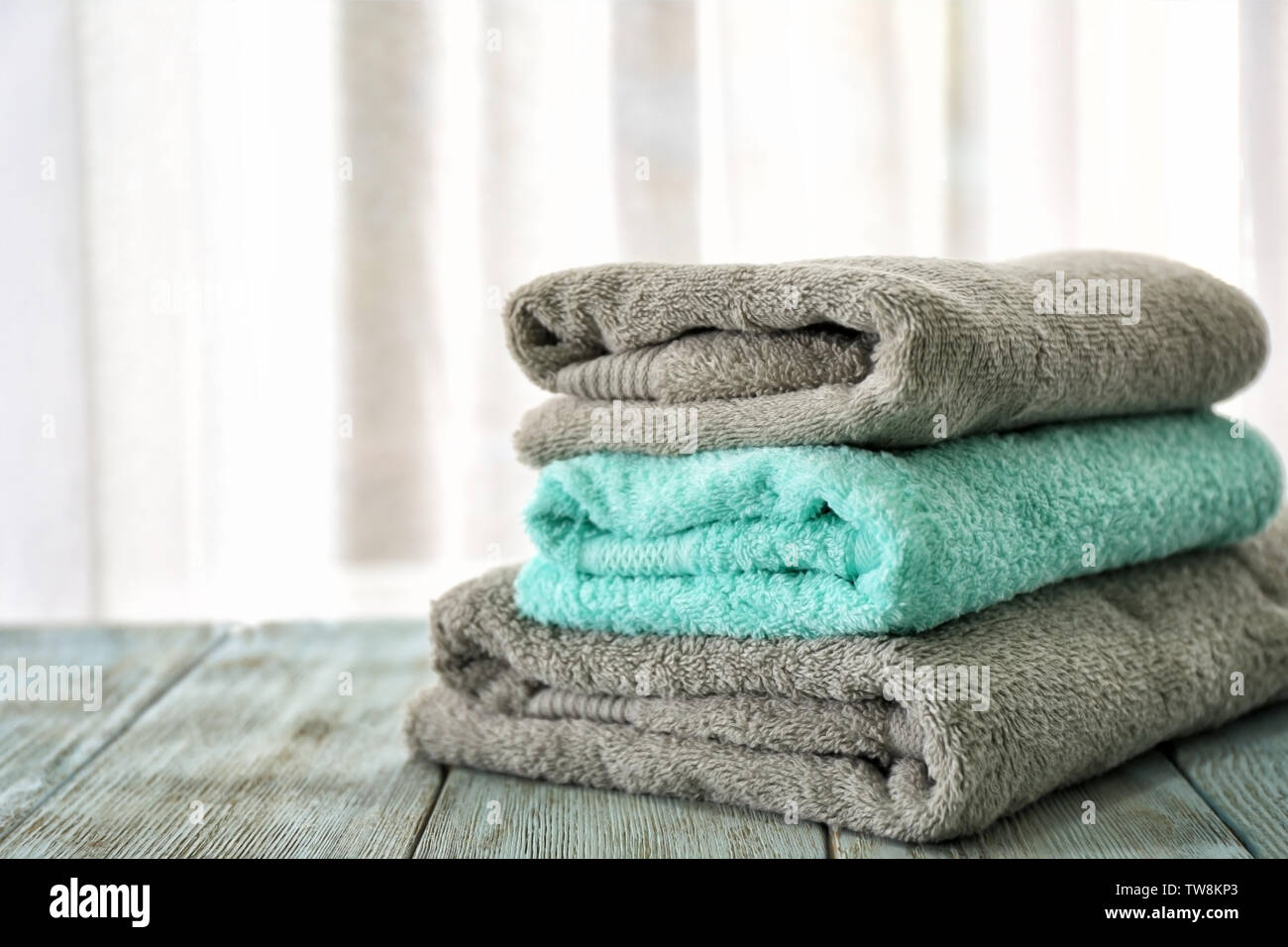 Stack of bath towels on table against light background Stock Photo - Alamy