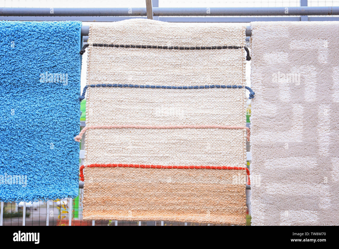 Different carpets hanging on rack outdoors Stock Photo - Alamy