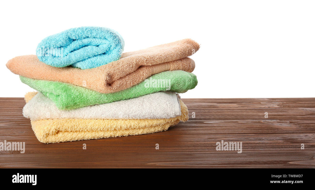 Folded towels on table against white background Stock Photo - Alamy