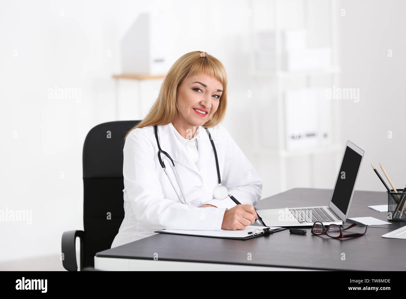 Female doctor filling up application form in consultation room Stock ...