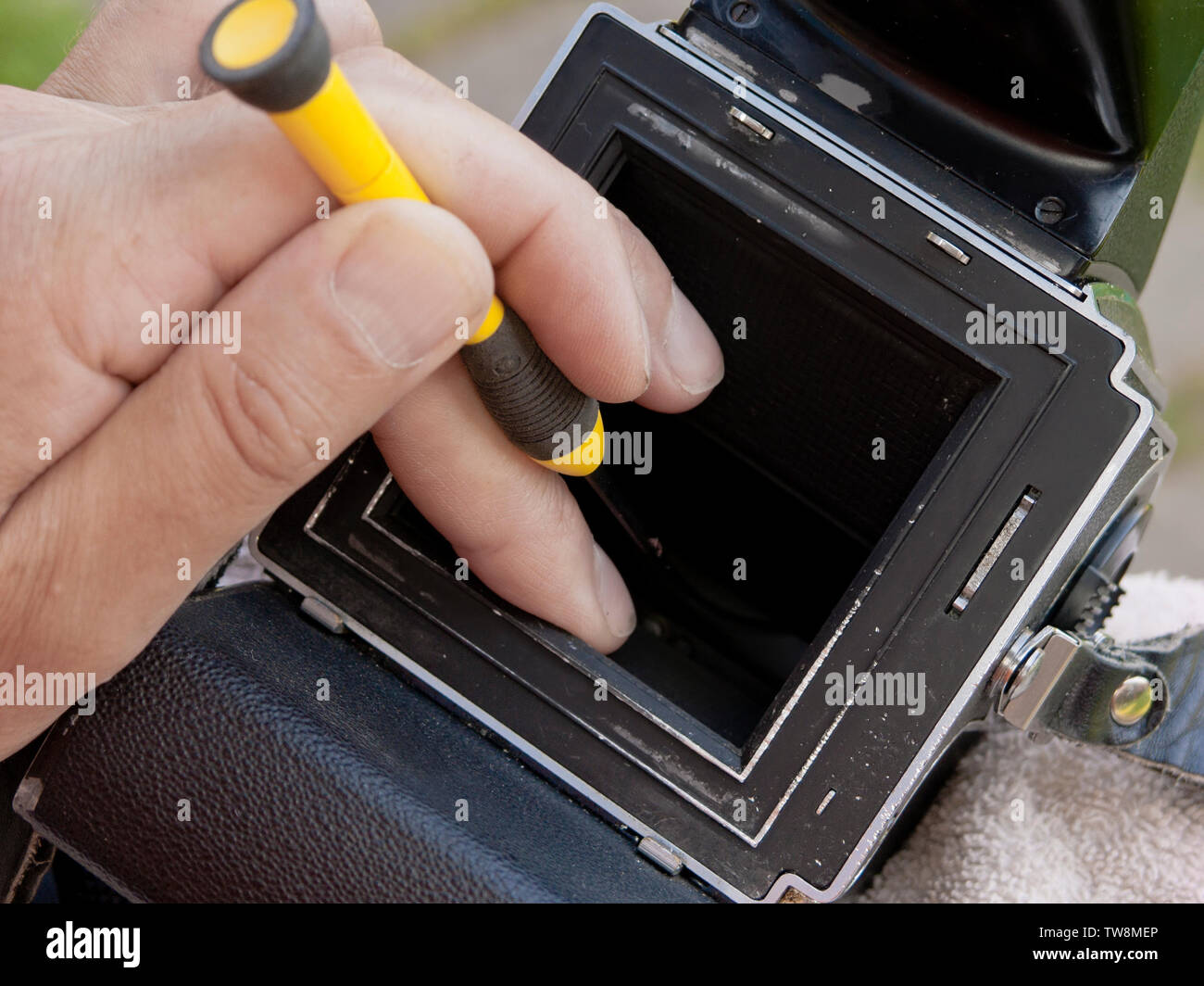 Hand with a screwdriver repairing an old film camera with open chamber ...