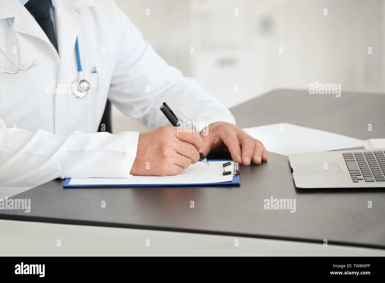 Male doctor filling up application form in consultation room, closeup ...