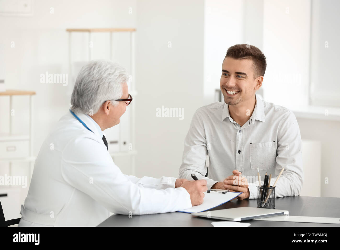 Male doctor consulting patient in clinic Stock Photo - Alamy