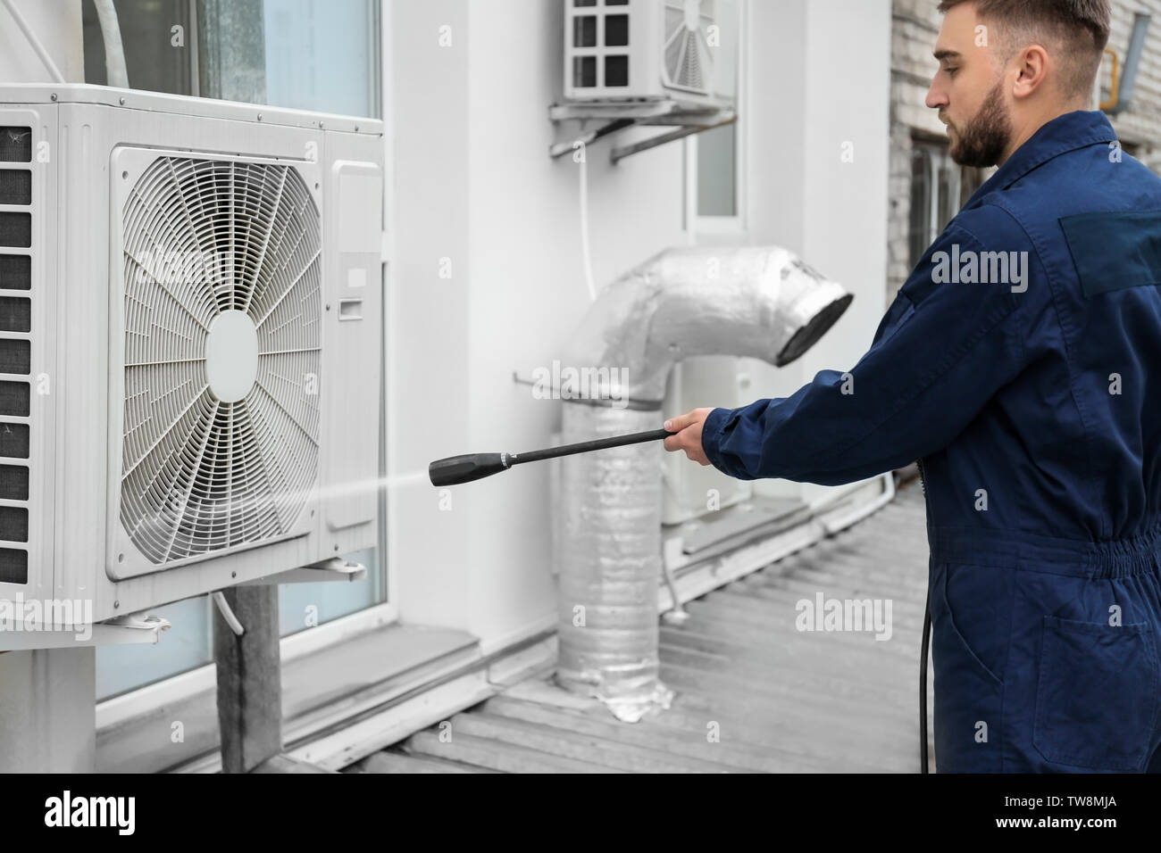 Male technician cleaning air conditioner outdoors Stock Photo - Alamy