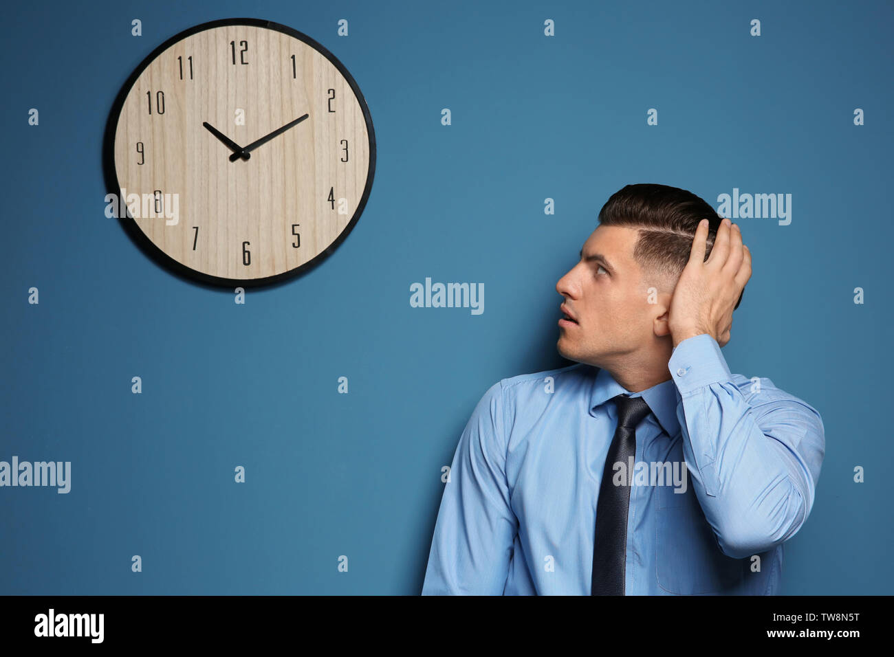 Shocked manager looking at clock hanging on wall Stock Photo - Alamy