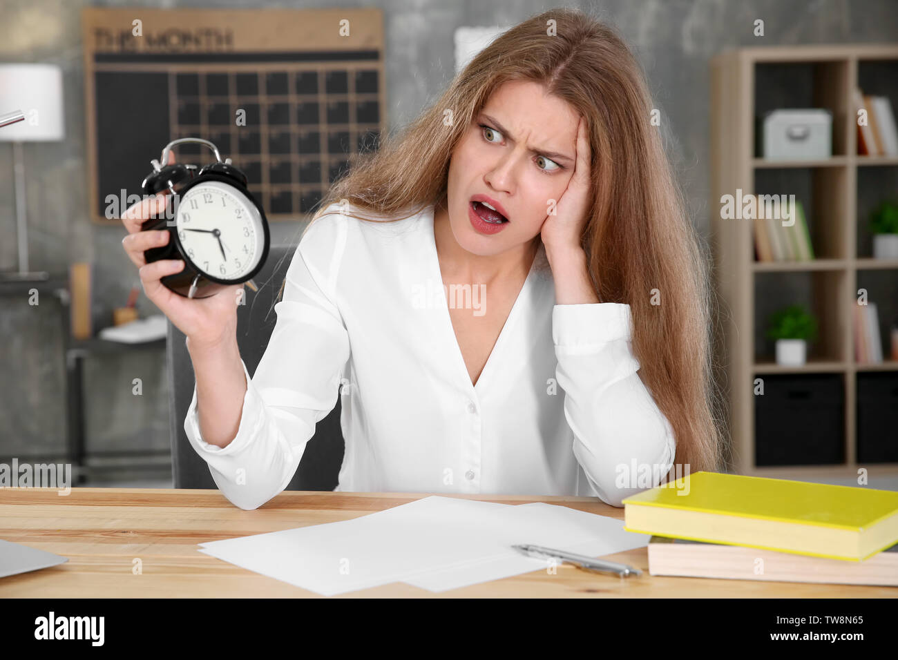 Shocked manager with alarm clock sitting at workplace Stock Photo - Alamy