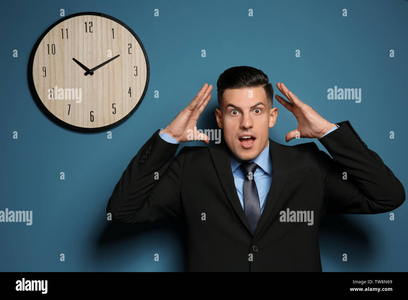 Shocked manager near wall with clock Stock Photo - Alamy