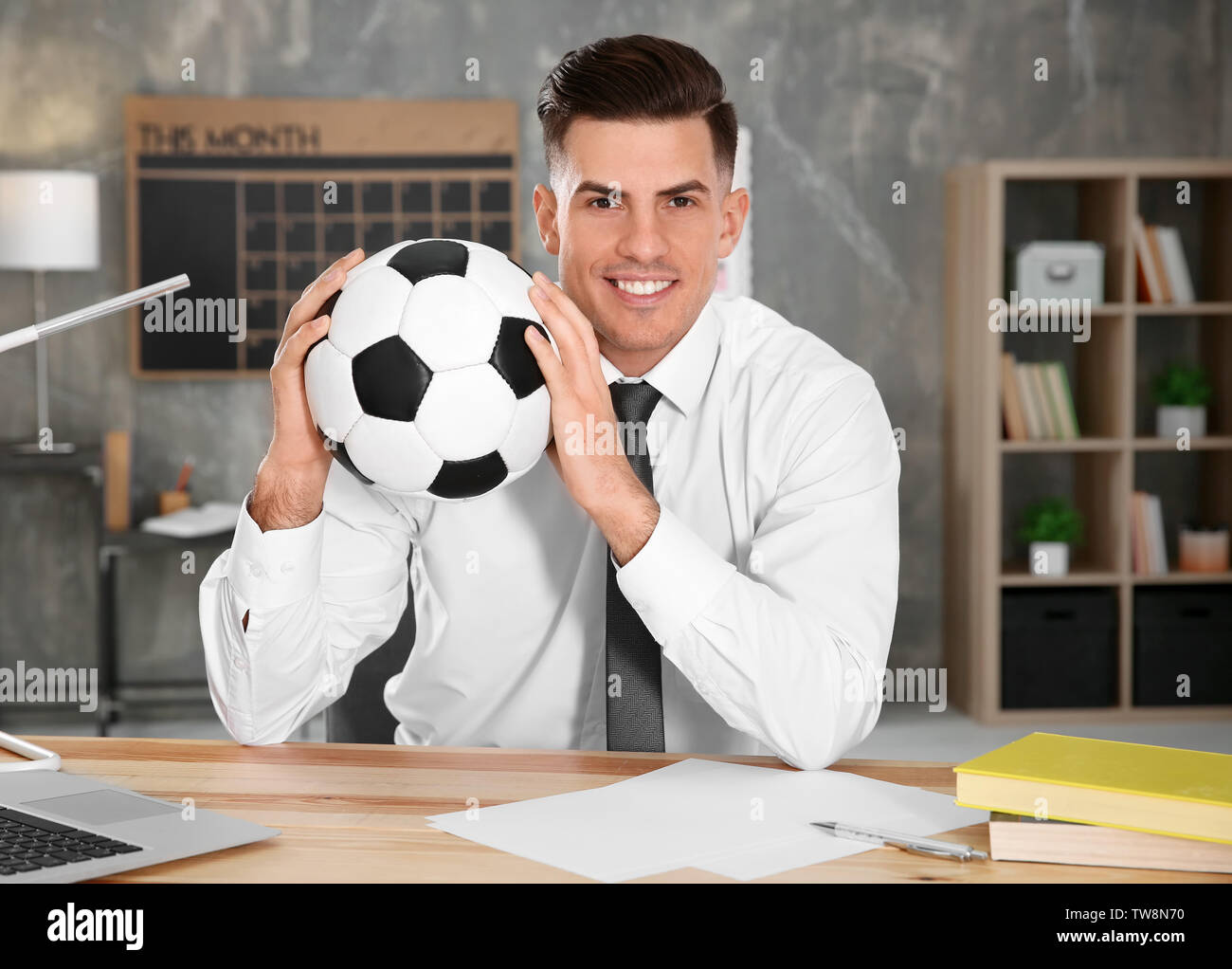 Handsome manager with soccer ball sitting at workplace Stock Photo - Alamy