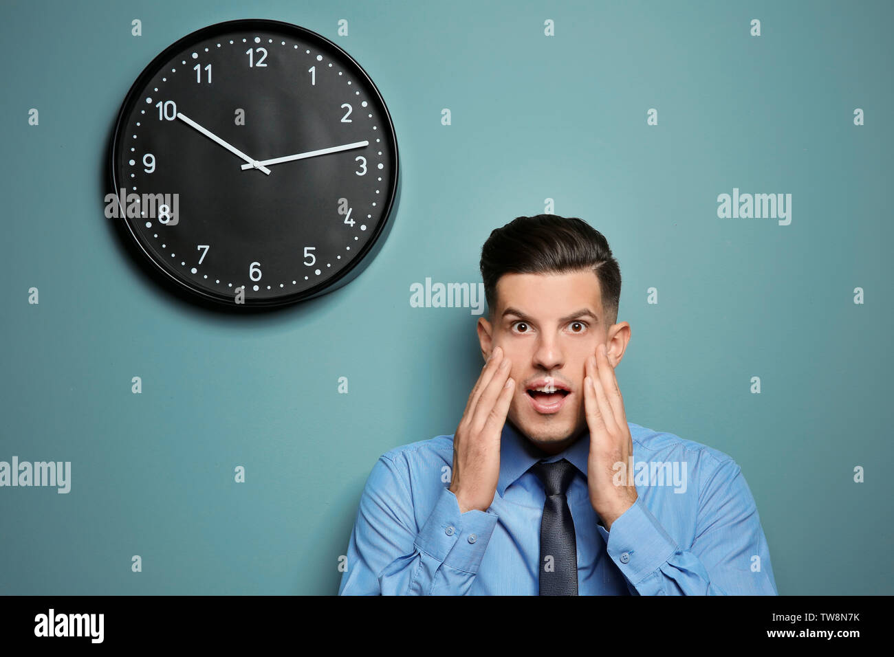 Shocked manager near wall with clock Stock Photo - Alamy