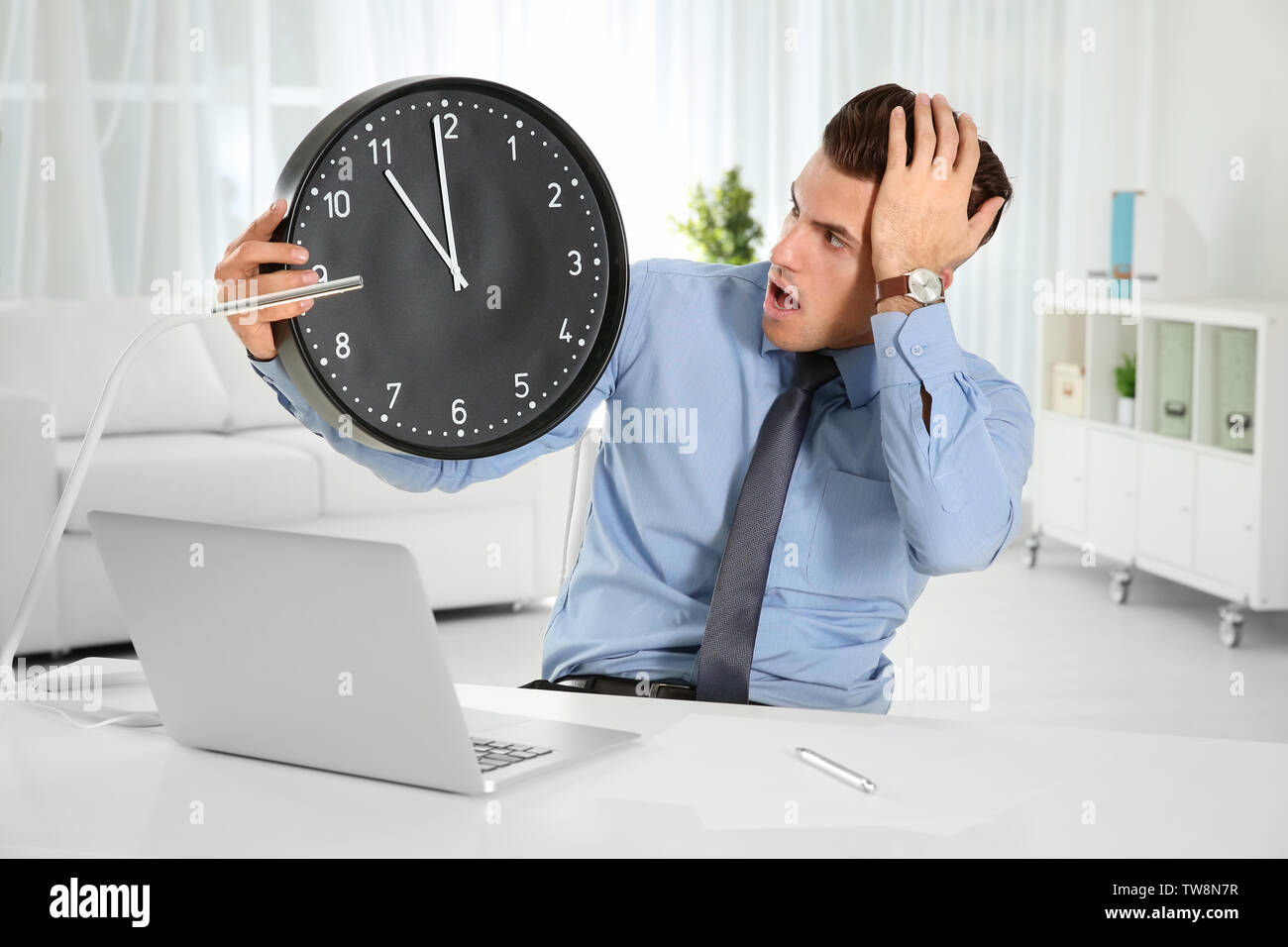 Shocked manager looking at clock in office Stock Photo - Alamy