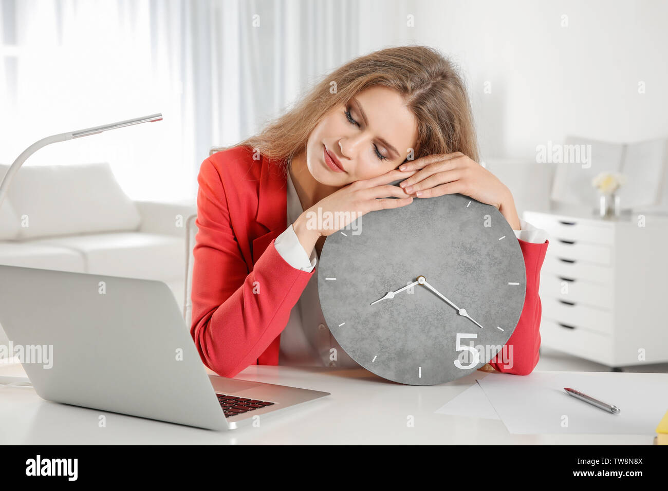 Tired manager with clock sitting at workplace Stock Photo - Alamy