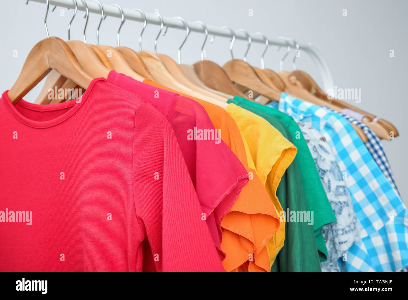 Stylish clothes hanging on wardrobe stand against light background ...