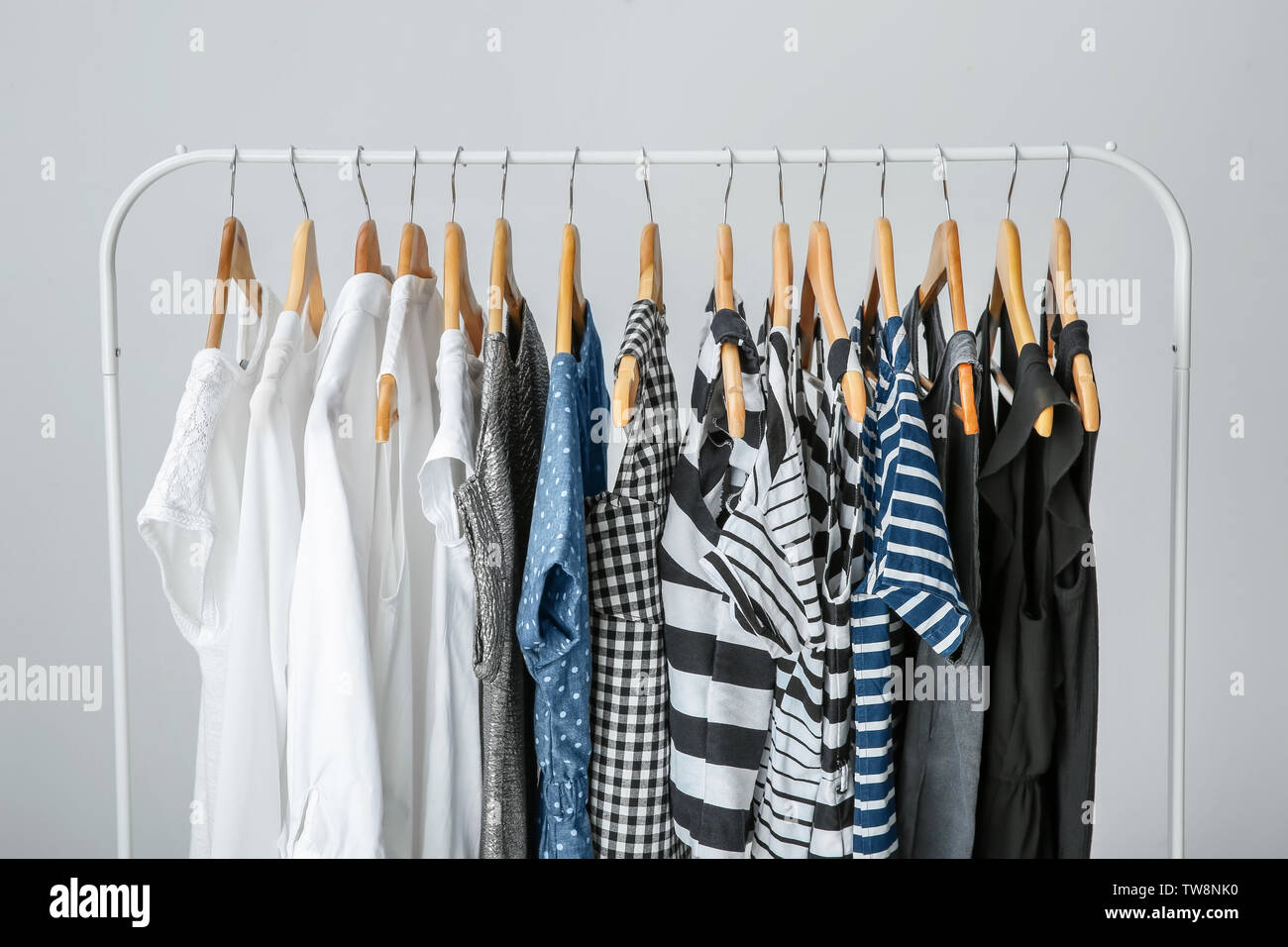 Stylish clothes hanging on wardrobe stand against light background ...