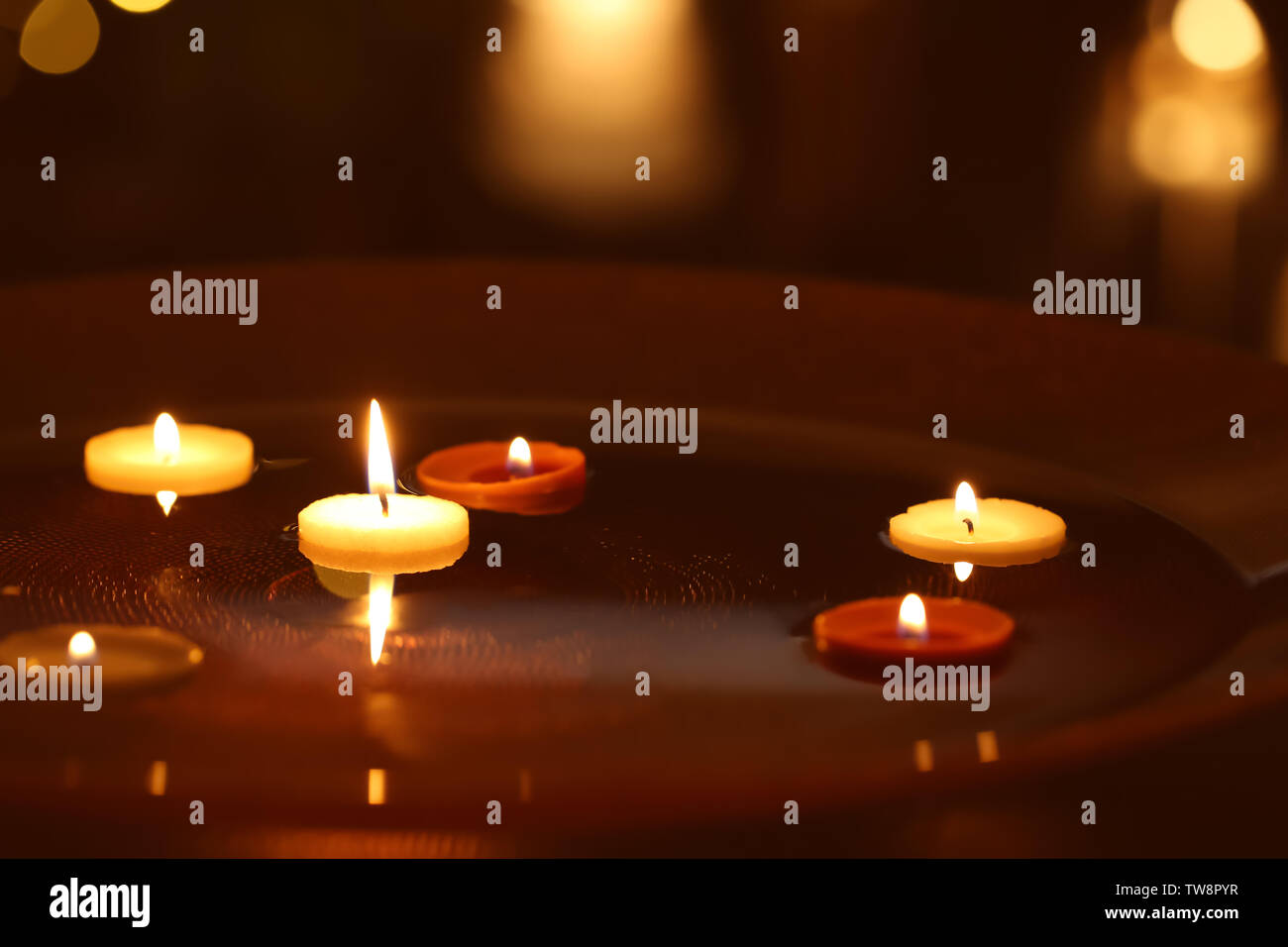 Small burning candles floating in plate with water Stock Photo - Alamy