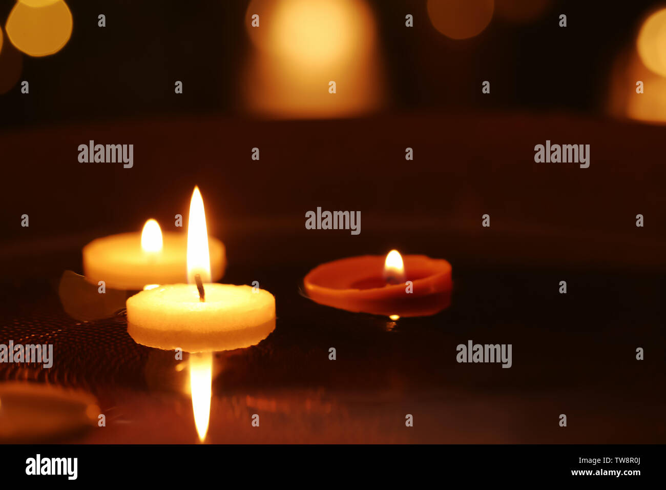 Small burning candles floating in plate with water, closeup Stock Photo ...