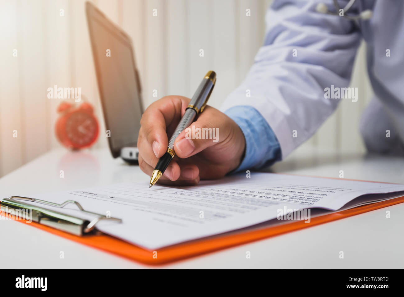 Doctor in gown uniform using a pen write on medical chart Stock Photo ...